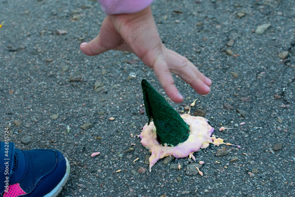 The child's hand reaches for the ice cream that has fallen on the ...