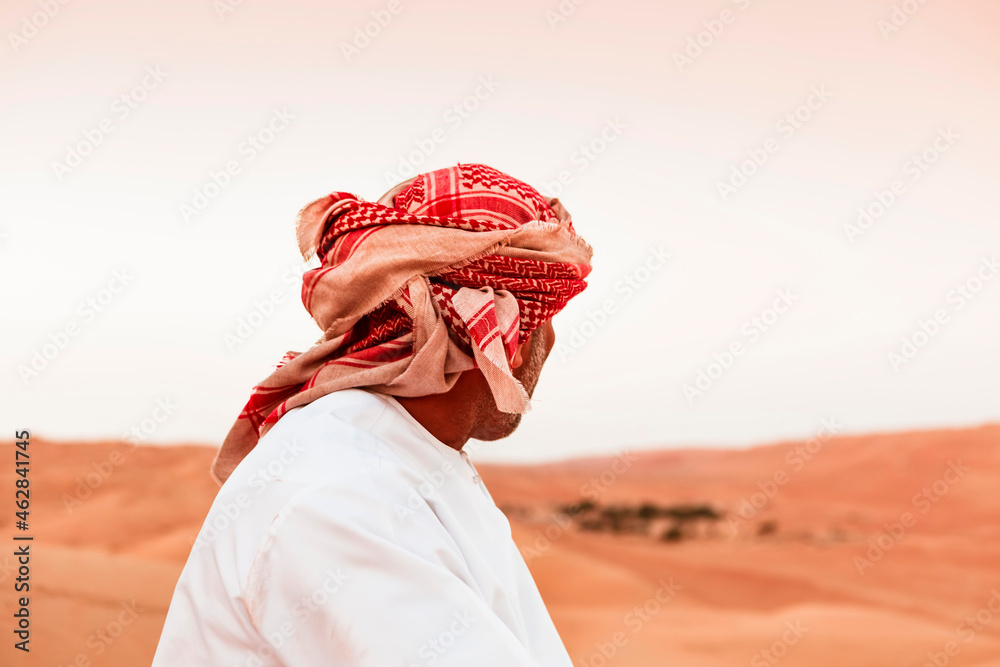 Bedouin in National dress standing in the desert, rear view, Wahiba ...