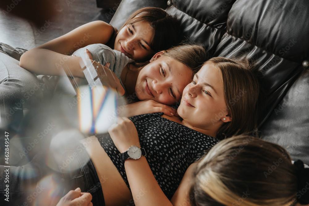 Smiling friends cuddling while lying on sofa bed at home Stock Photo ...