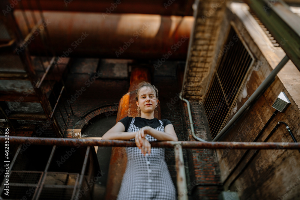 Teenage girl standing by railing against abandoned building Stock Photo ...