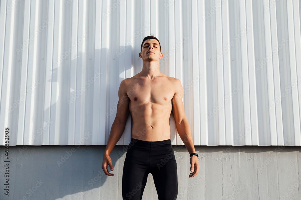 Shirtless man standing against wall outdoors Stock Photo | Adobe Stock
