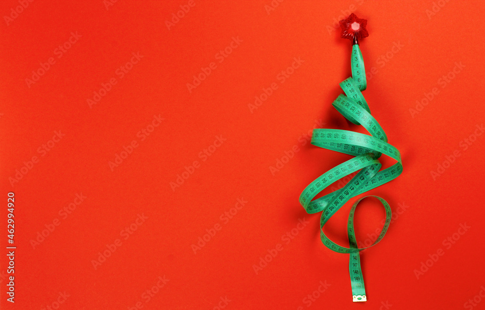 Christmas tree made of measuring tape on a red background with copy ...