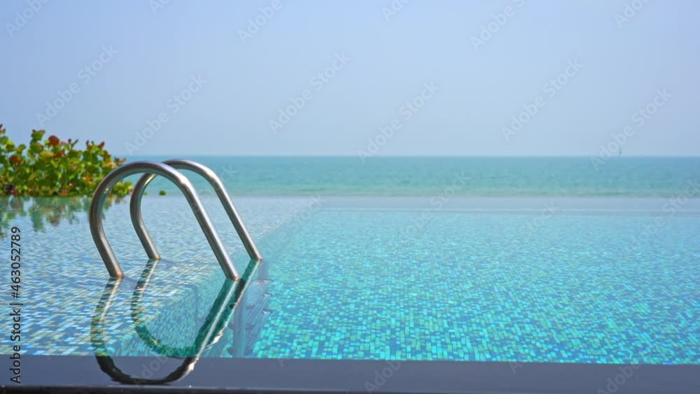 Crystal clear water of luxury resort infinity swimming pool with ladder ...
