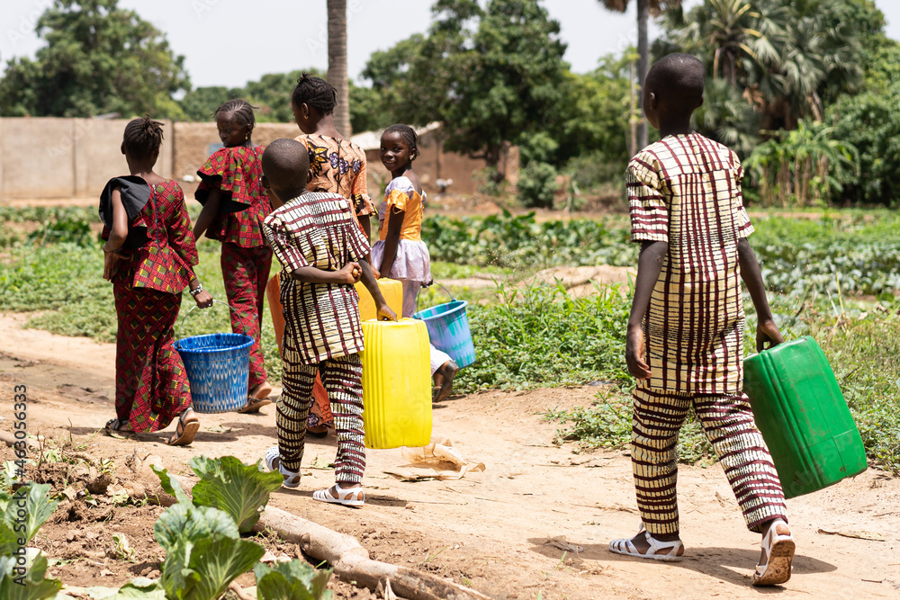 Foto de Group of black African children carrying empty water containers ...