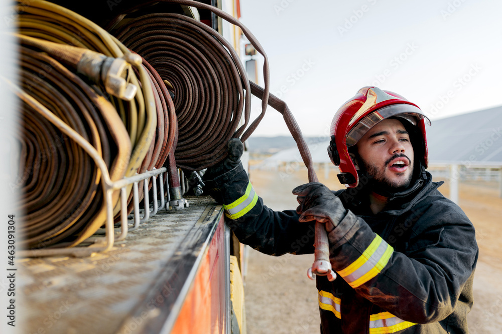 Firefighter pulling a fire hose from the truck Stock Photo | Adobe Stock