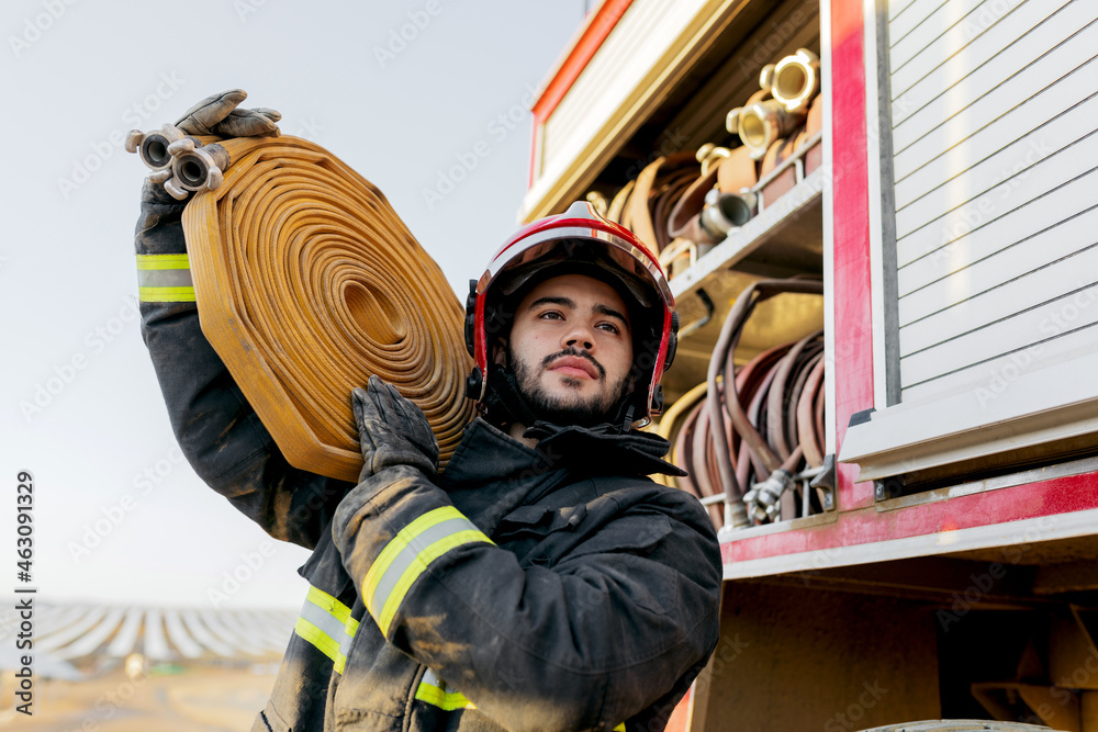 Fireman carrying fire hose on shoulder Stock Photo | Adobe Stock
