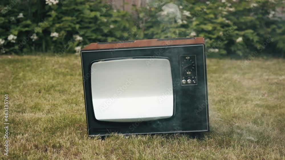 Old vintage retro TV stands on the grass. There is interference on the ...