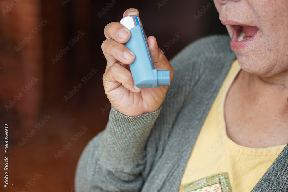 Female senior patient uses blue asthma inhaler for relief asthma ...