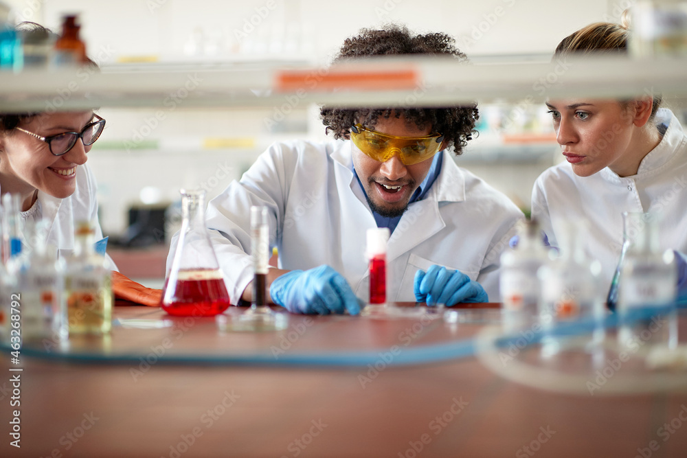Lab workers looking chemical reaction in glassware Stock Photo | Adobe ...