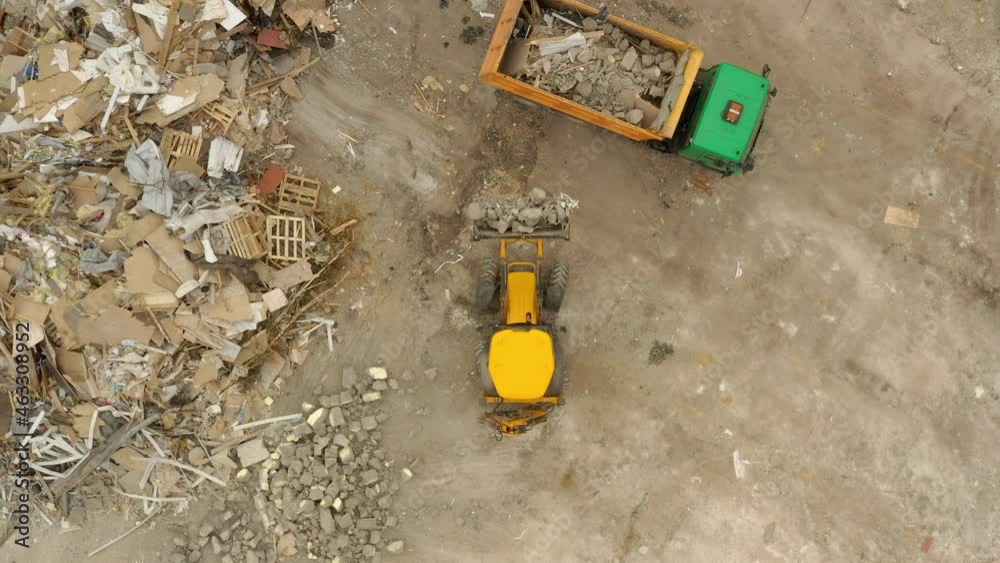 Excavator is loading construction debris into a dump truck at a ...