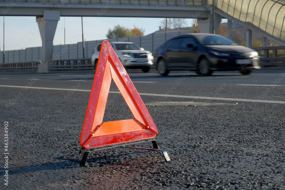 An emergency stop sign on the background of a road with cars and an ...