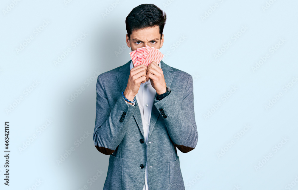 Young hispanic business man covering face with cards skeptic and ...