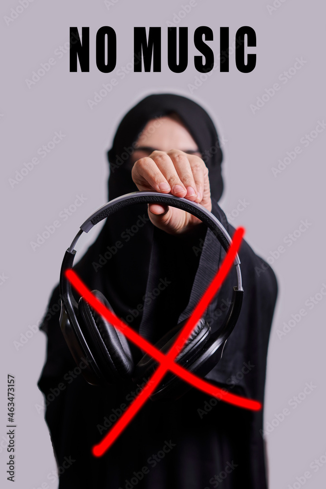 Muslim woman in traditional hijab clothing holding black wireless ...