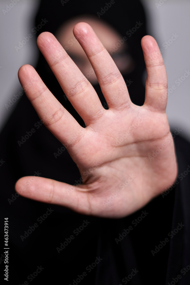 A Muslim woman in traditional black clothing nikab showing stop hand ...