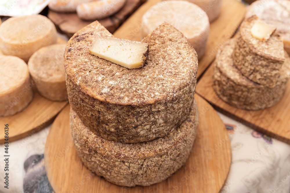 Wheels of crafted natural cheese at the market stall, a piece of ...