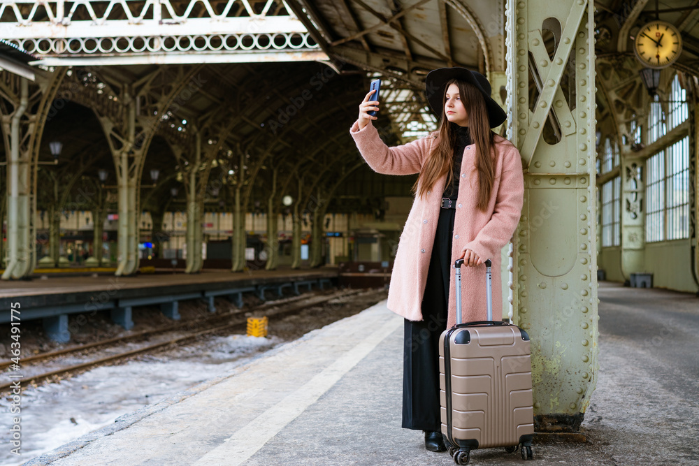 Happy young woman on platform of railway station in pink coat and black ...