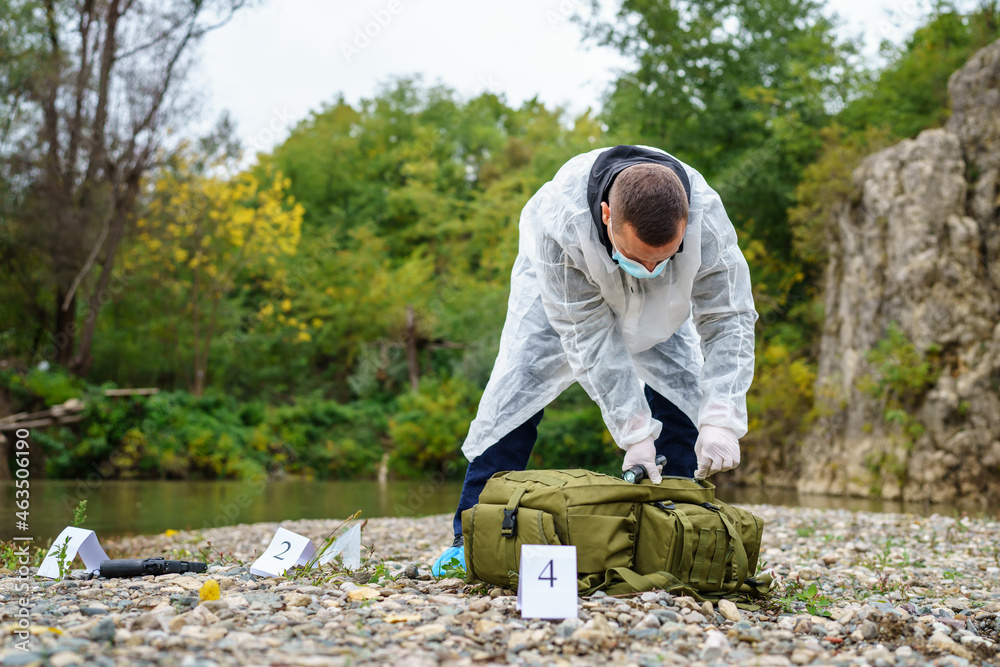 Forensic police investigator collecting evidence at the crime scene by ...