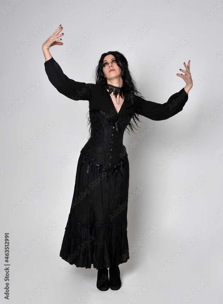 Full length portrait of dark haired woman wearing black victorian witch ...