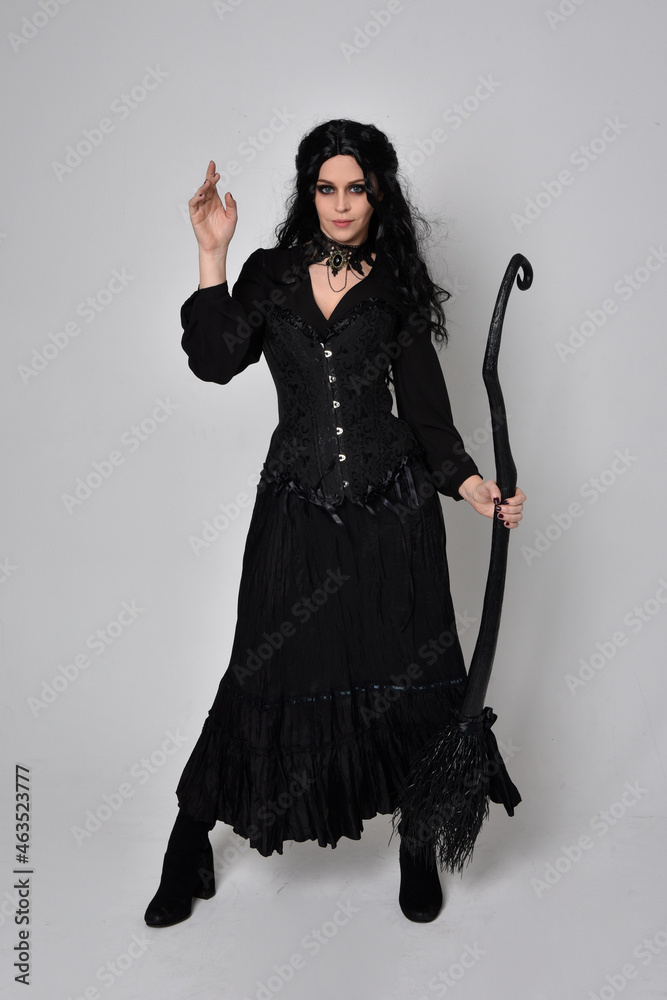 Full length portrait of dark haired woman wearing black victorian witch ...