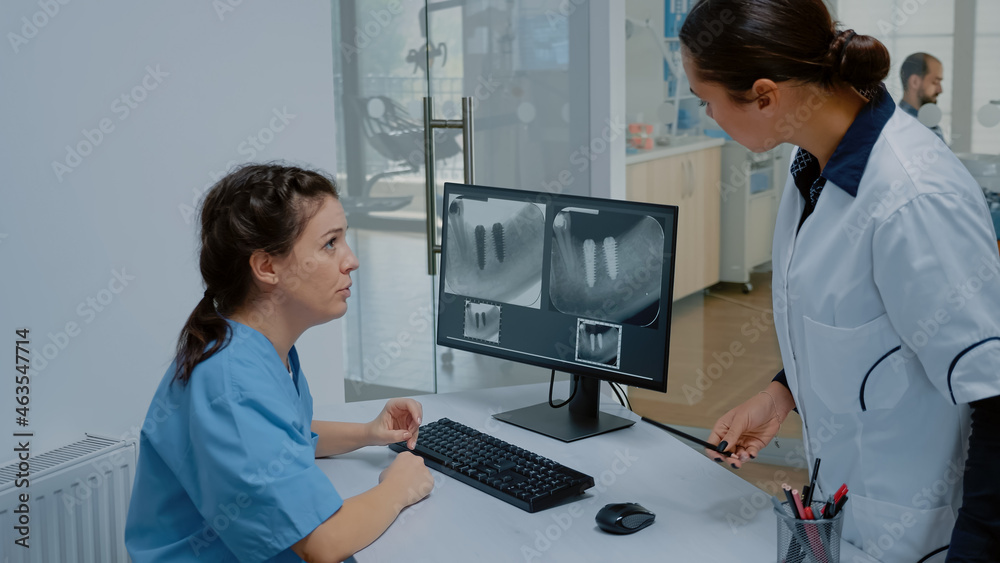 Stomatologist and nurse examining dental x ray scan on computer monitor ...