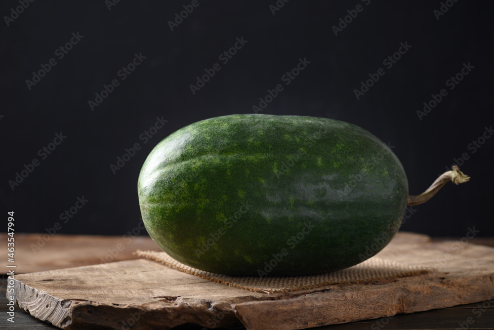 Wax gourd, ash gourd or winter melon on wooden with black background ...