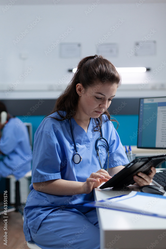 Pharmacist nurse looking at tablet computer analyzing sickness ...