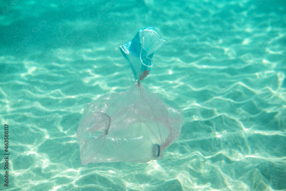 Ocean pollution. Personal protective mask, plastic bottle and bag ...