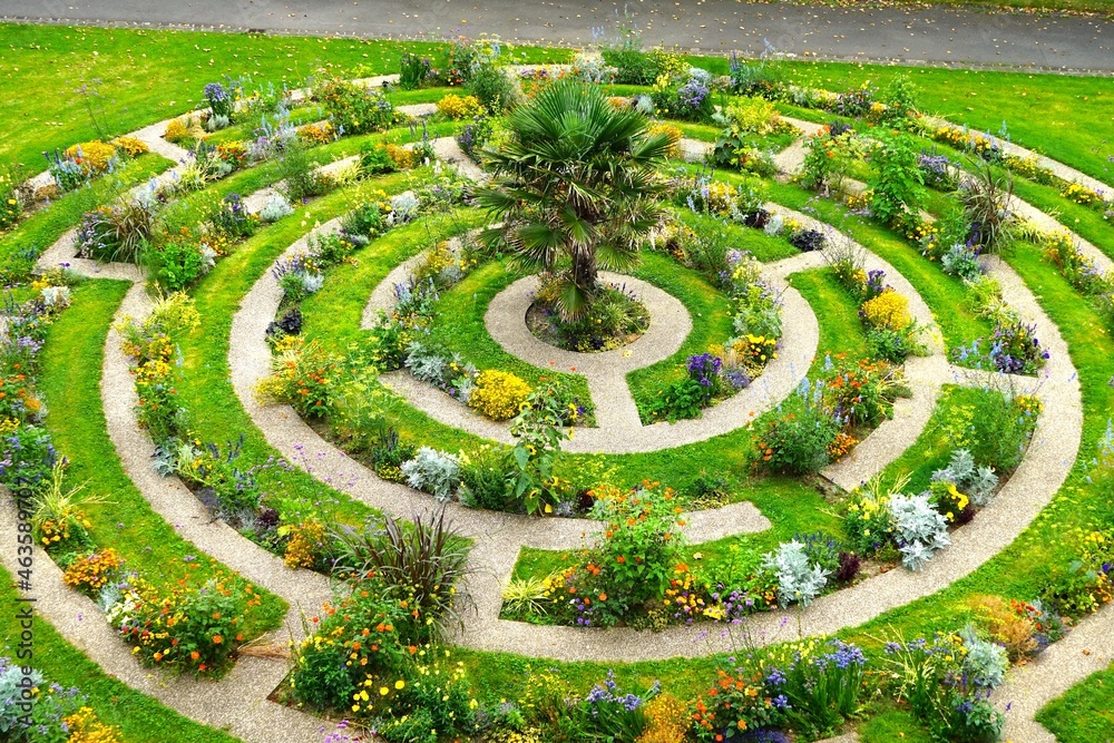Kreisförmiges Blumenbeet mit Labyrinth und einer Palme in der Mitte ...
