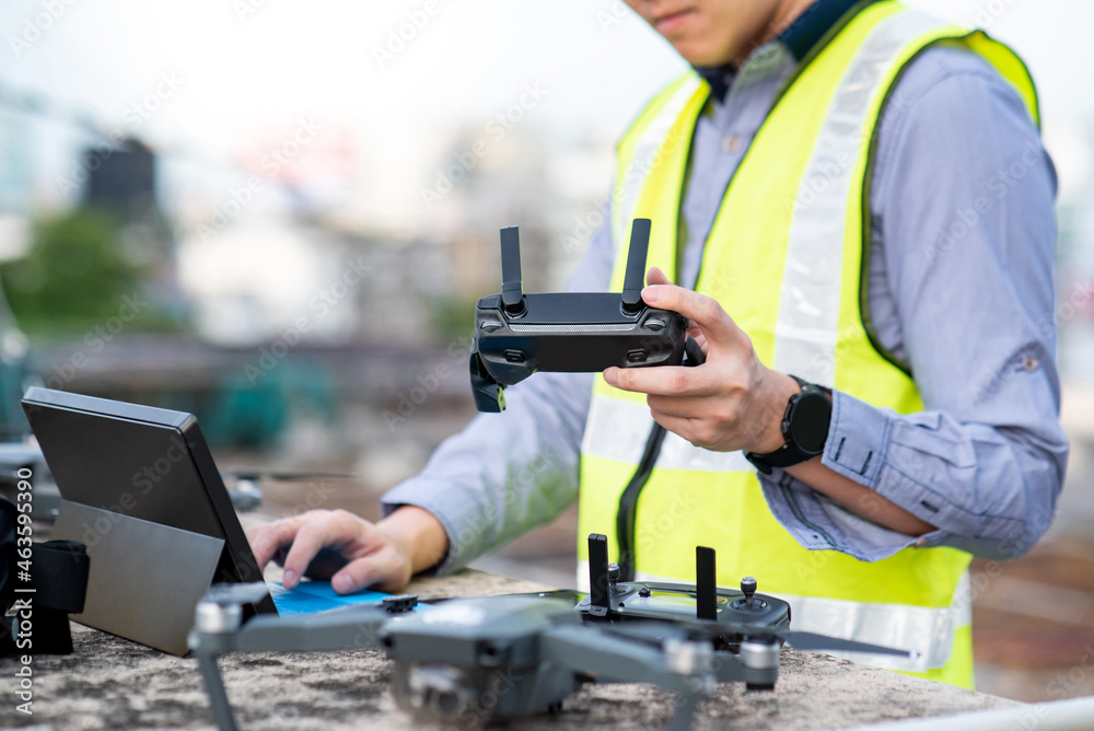 Male worker using drone, remote control and laptop computer at ...