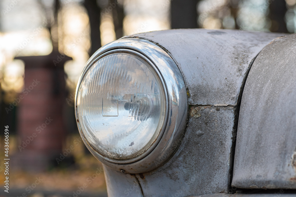 side view of a round headlight of a retro car with traces of wear and ...