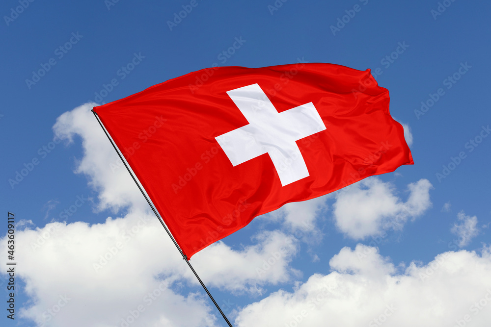 Switzerland flag isolated on the blue sky background. close up waving ...