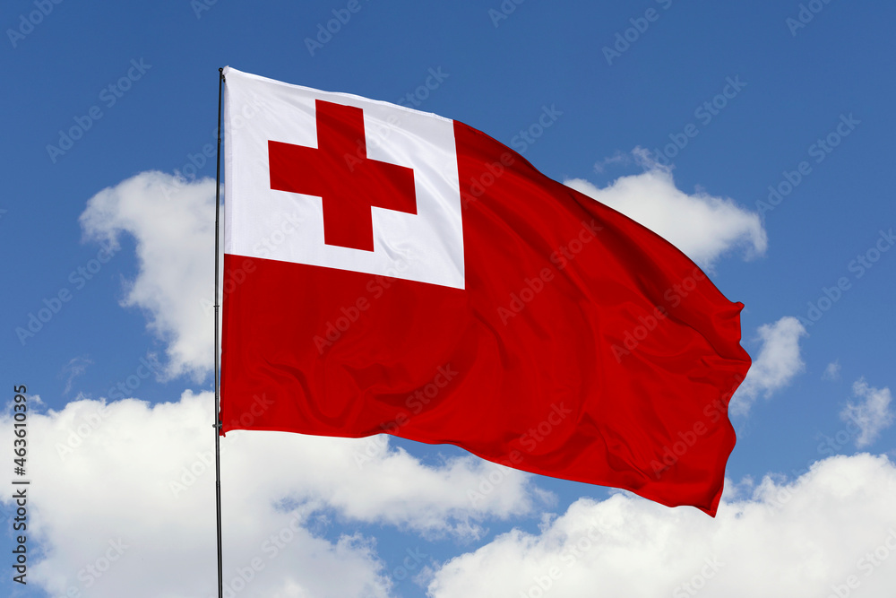 Tonga flag isolated on the blue sky background. close up waving flag of Tonga. flag symbols of ...