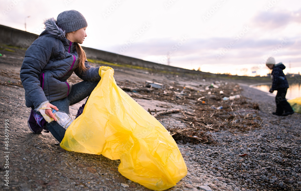 Preteen girl cleaning polluted sea shore from plastic garbage with her ...