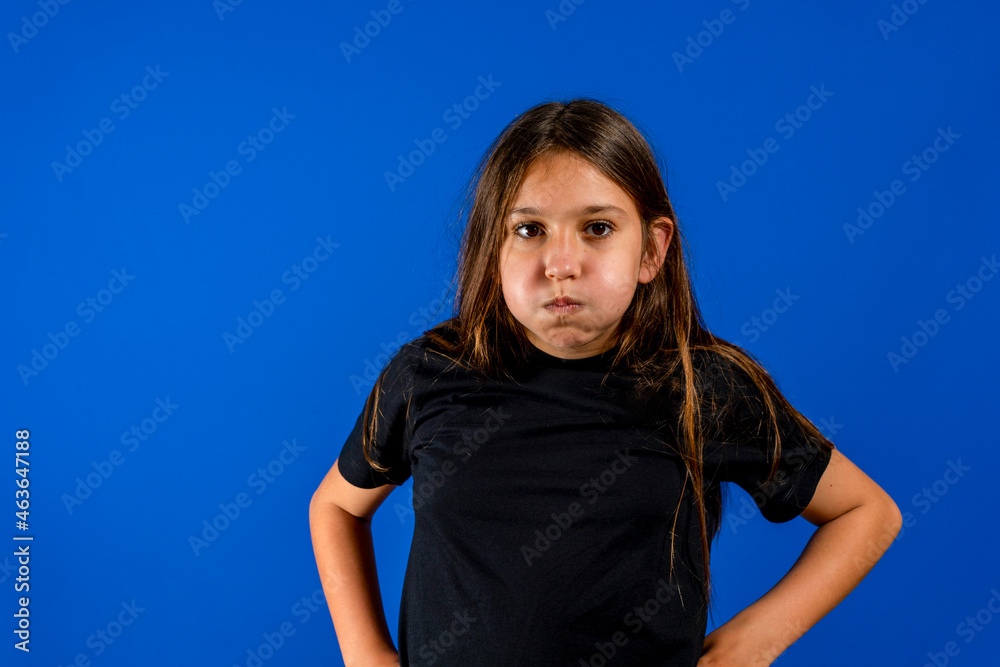 Poster The little girl puffed out his cheeks isolated on blue studio ...