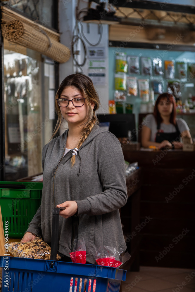 Chica joven comprando en local de productos naturales y detrás del ...