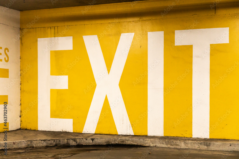 Yellow exit sign painted onto wall of underground car parking facility ...