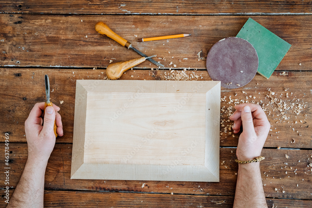 A person processes a rectangular wooden surface, sawdust is lying ...