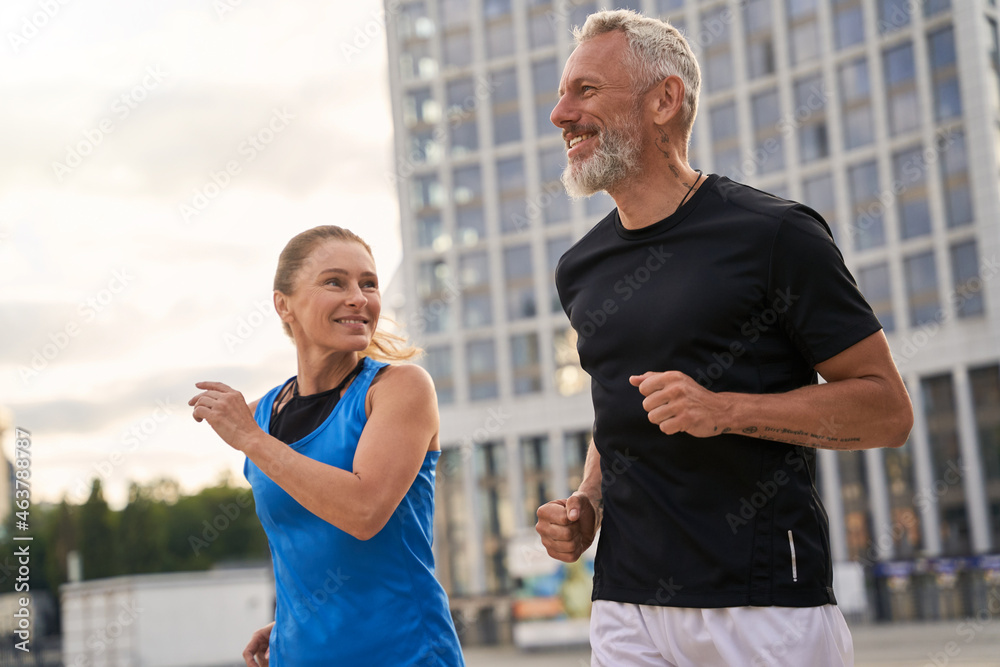 Portrait of active middle aged couple, man and woman in sportswear ...