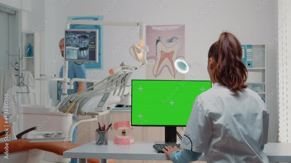 Dentist using computer with horizontal green screen on display ...