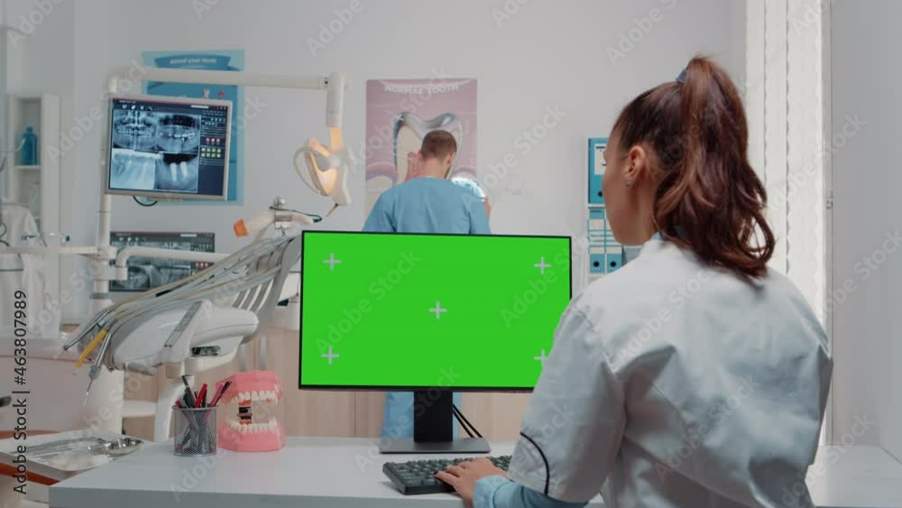 Woman using keyboard and computer with green screen in dental cabinet ...