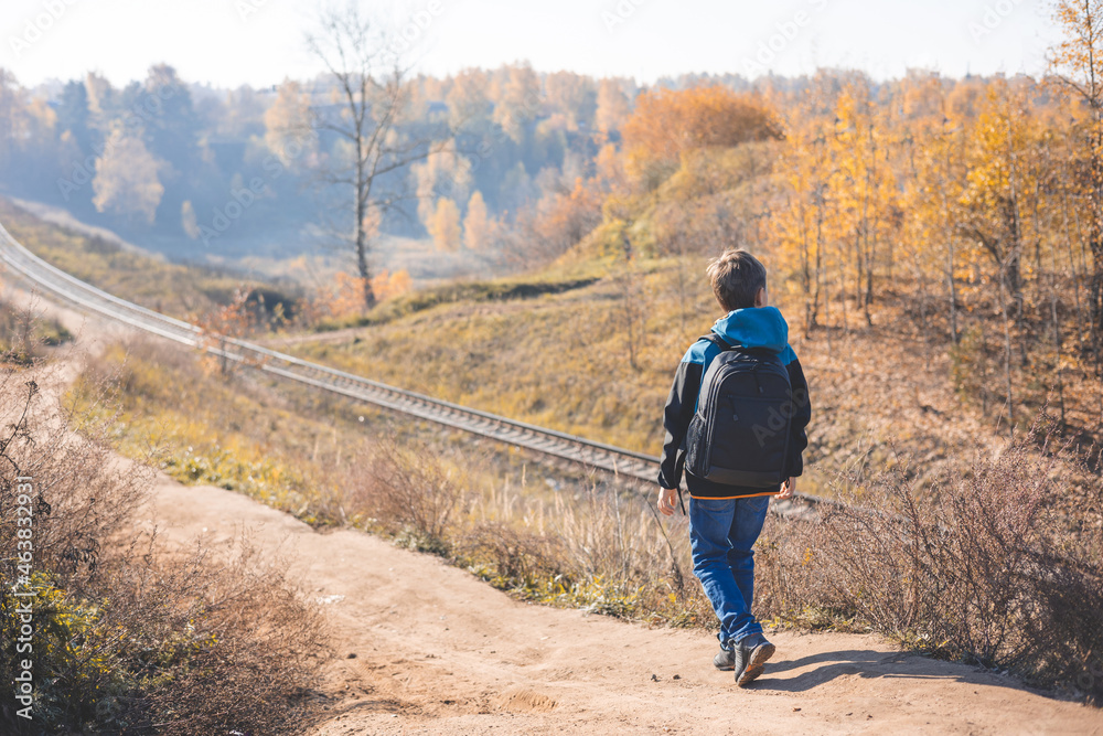 Teenager boy with backpack walking on path in autumn park. Active ...