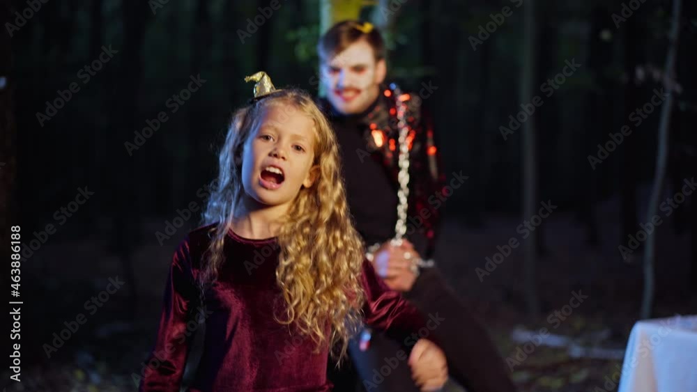 Excited happy little girl dancing catching scary vampire in dark forest ...