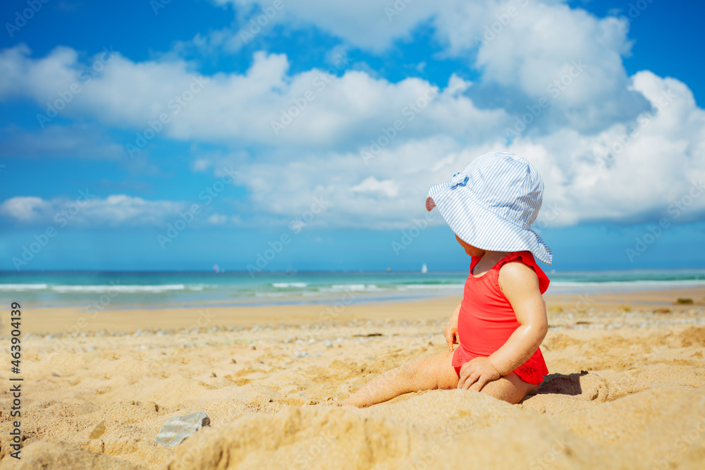 Cute baby girl in red swimsuit sit on sand beach Stock Photo | Adobe Stock