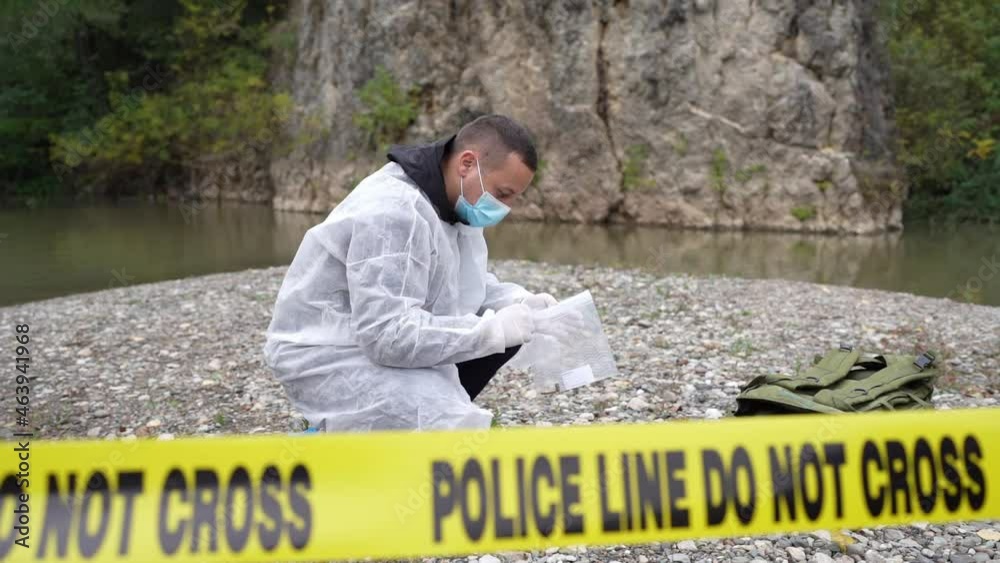 Forensic police investigator collecting evidence at the crime scene by ...