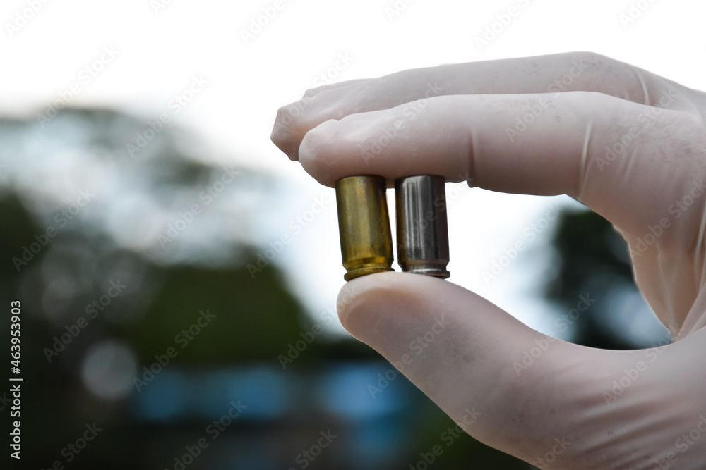 Forensic officers holds physical evidence which is the bullet shell up ...
