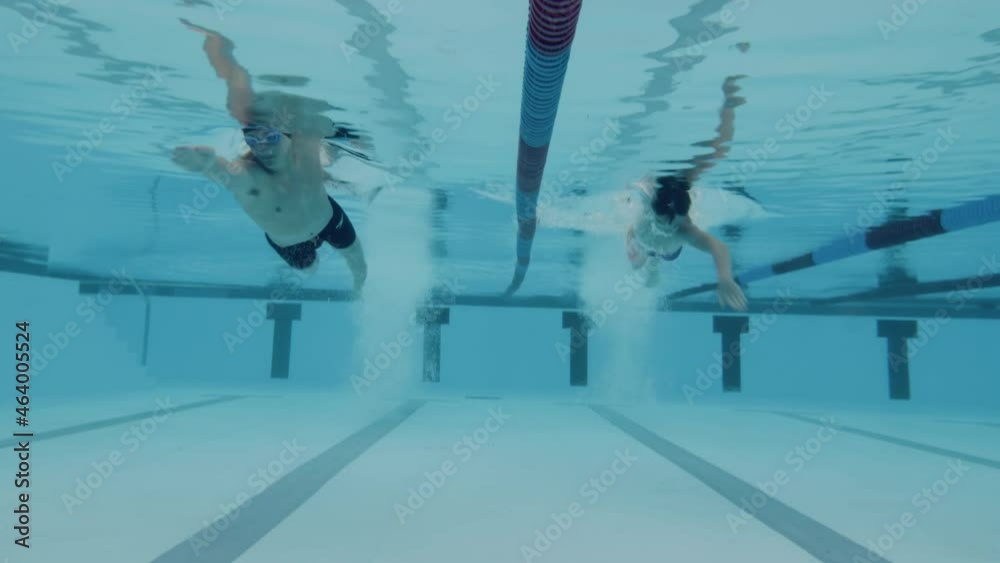 Underwater shot of two Caucasian swimmers immersing into the water and ...