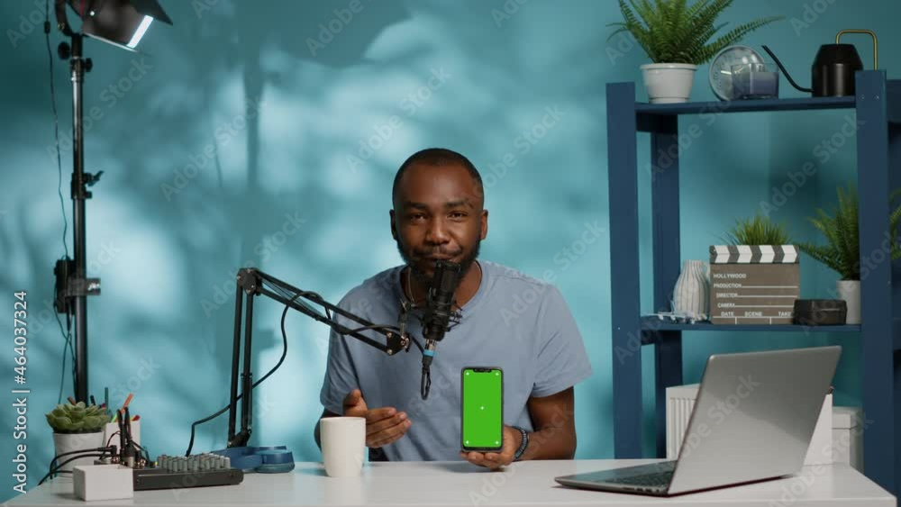 Influencer holding smartphone with green screen on display while ...