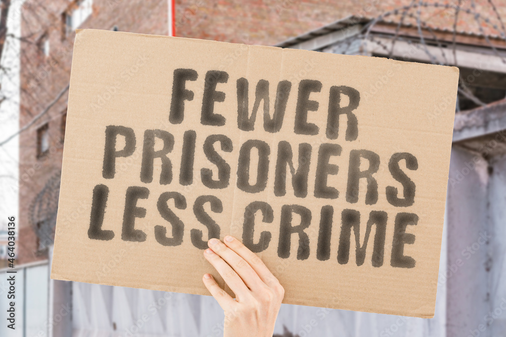 The phrase " Fewer Prisoners, Less Crime " on a banner in men's hand ...