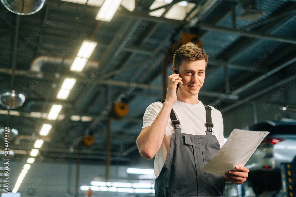 Low-angle view of smiling handsome young mechanic male wearing uniform ...