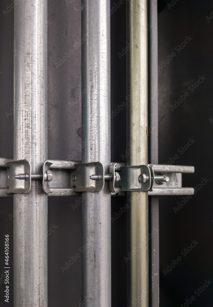 The group of the metal pipe is along the building wall with the metal ...